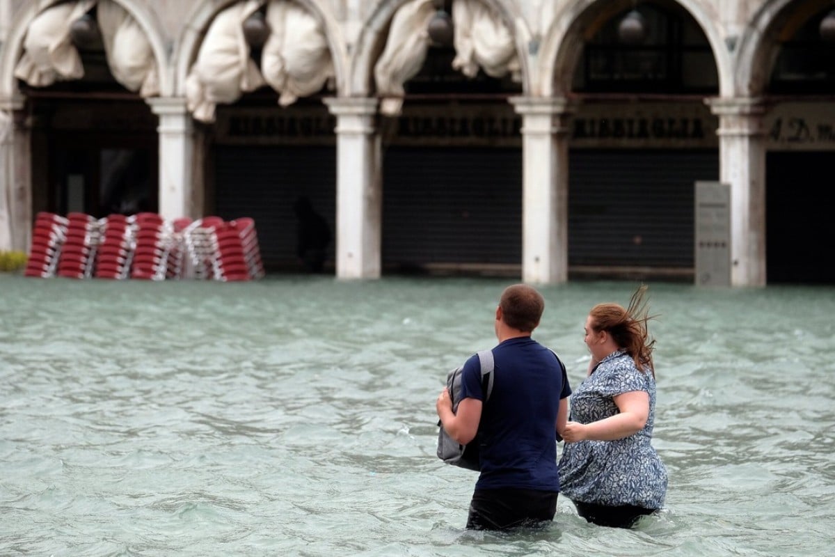 Tourists wade through Venice as 70 per cent of city is immersed by the ...